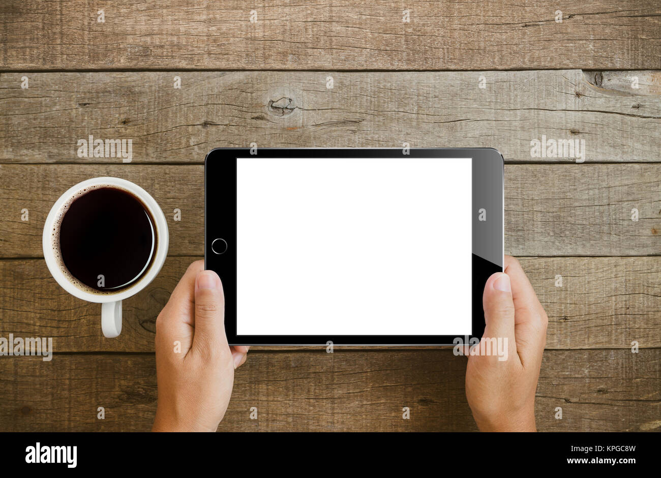 hand holding tablet on wood table Stock Photo - Alamy