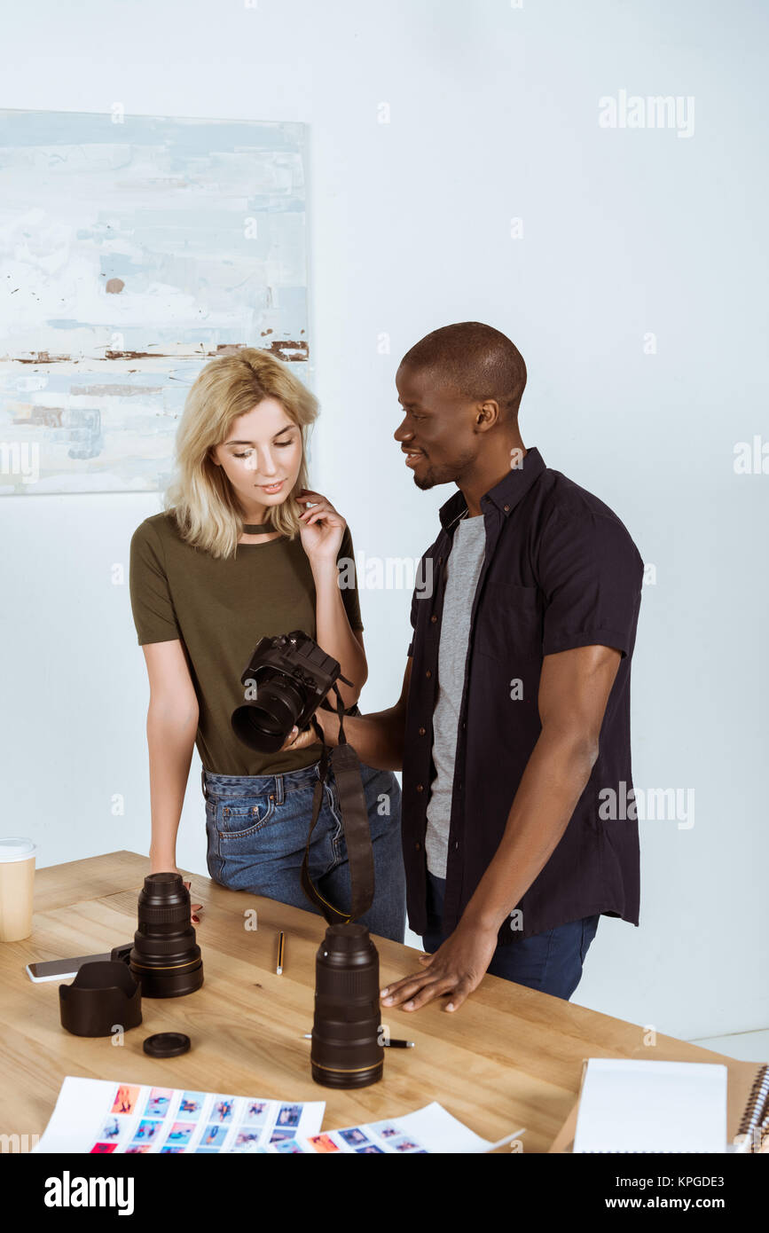interracial photographers talking about photo cameras at workplace in ...