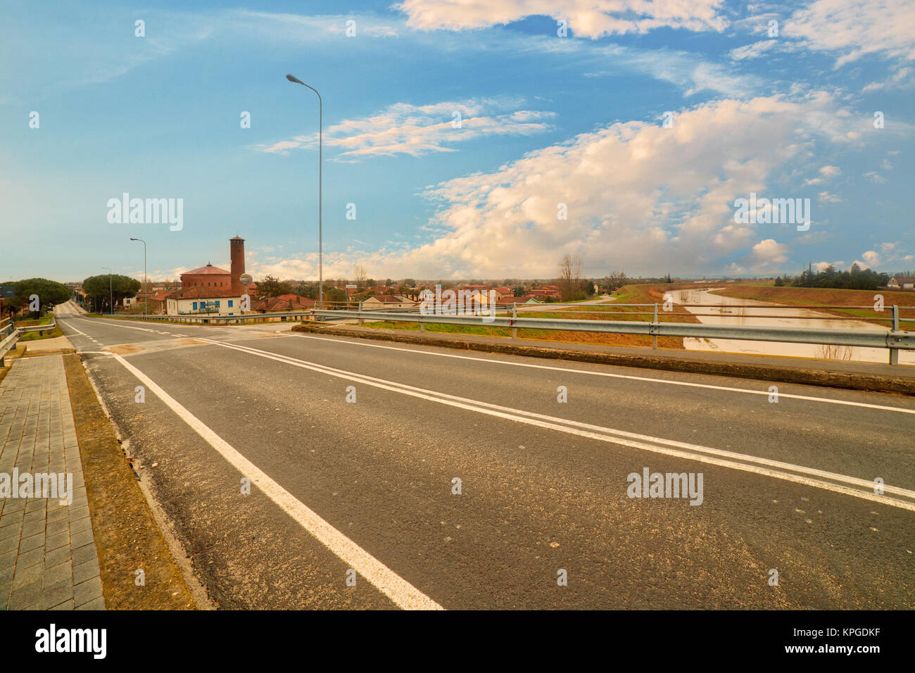 road bridge on Muddy waters of a swollen river along small village in ...
