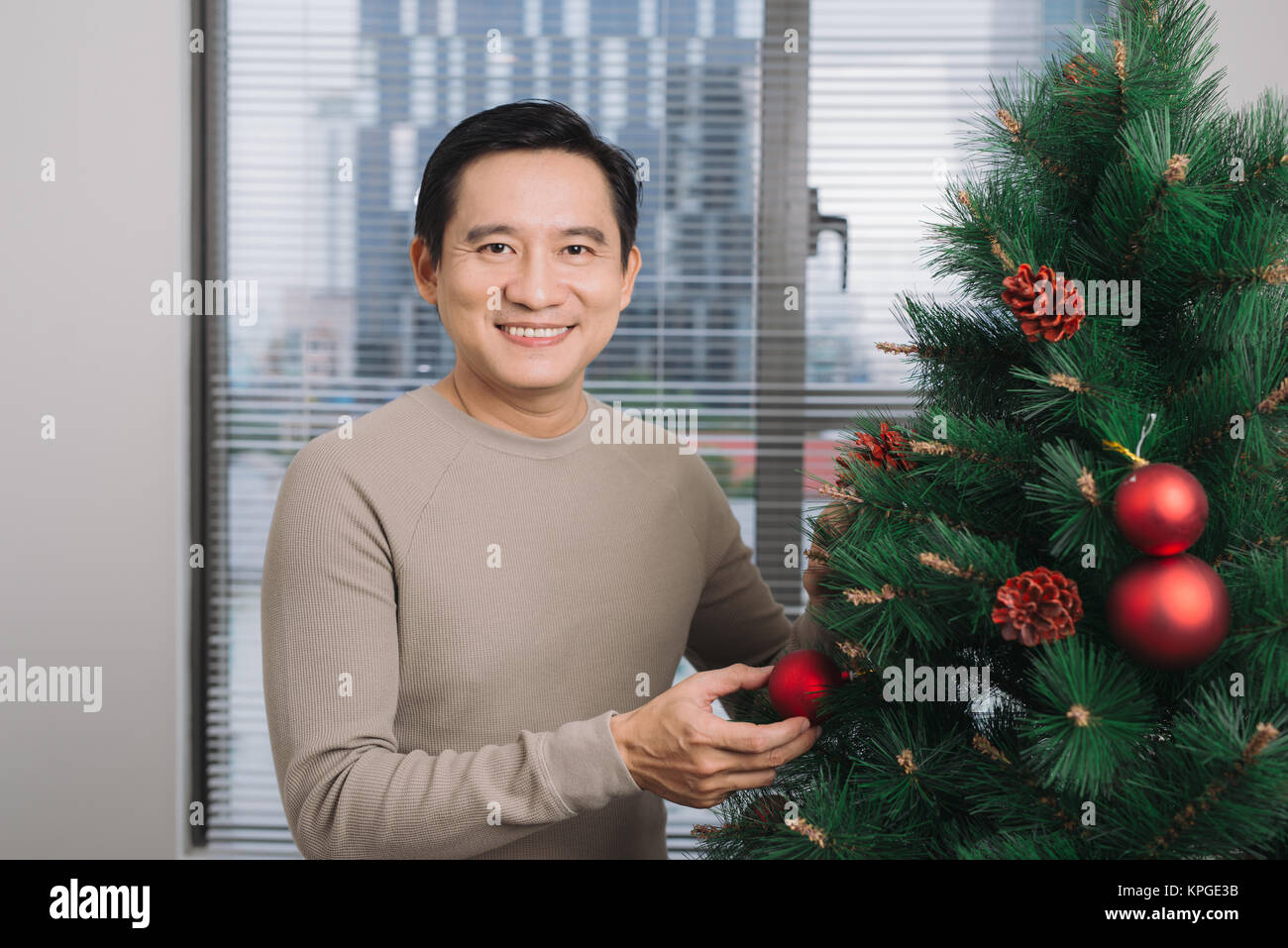 Christmas. Asian man standing new christmas tree at home celebrating ...