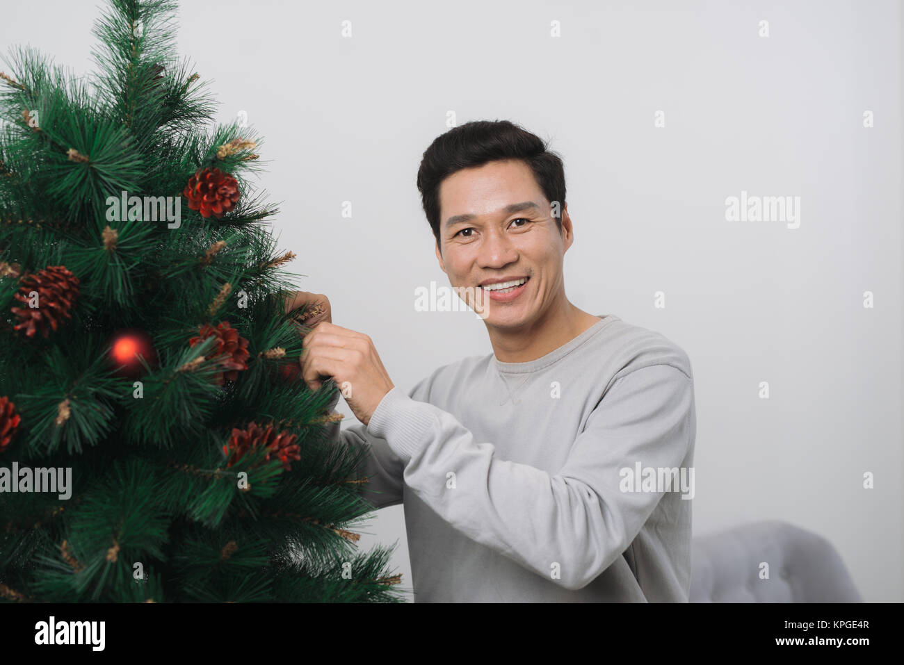 Christmas. Asian man standing new christmas tree at home celebrating ...