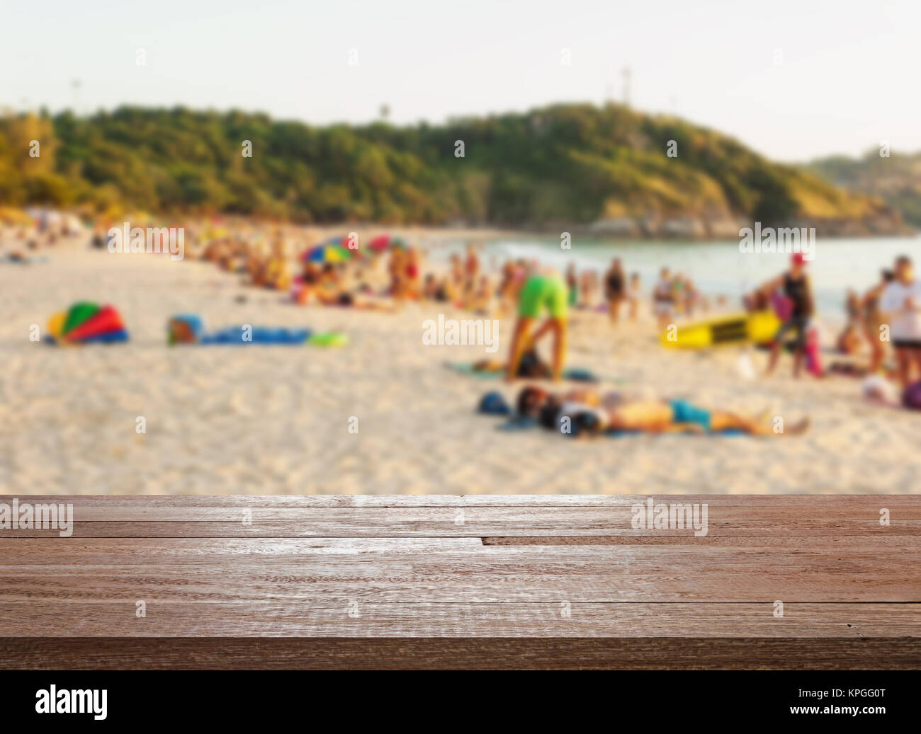 Wood table top on blurred sea and sand beach with some people in ...