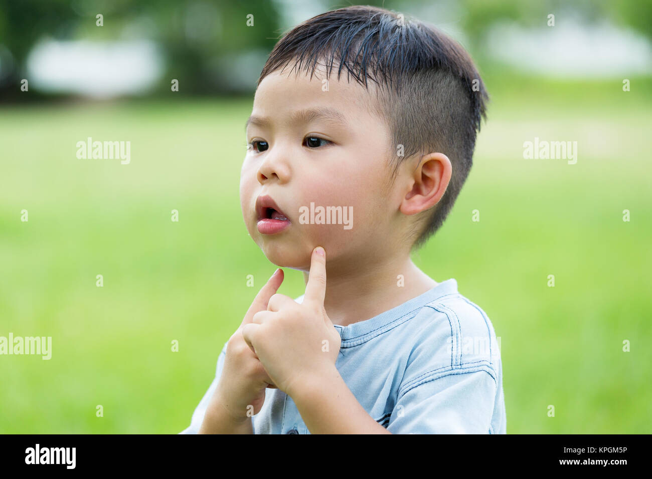 Little with finger touch on his cheek Stock Photo - Alamy