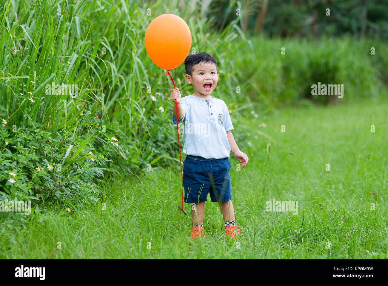 Asian kid catch up with his balloon Stock Photo - Alamy