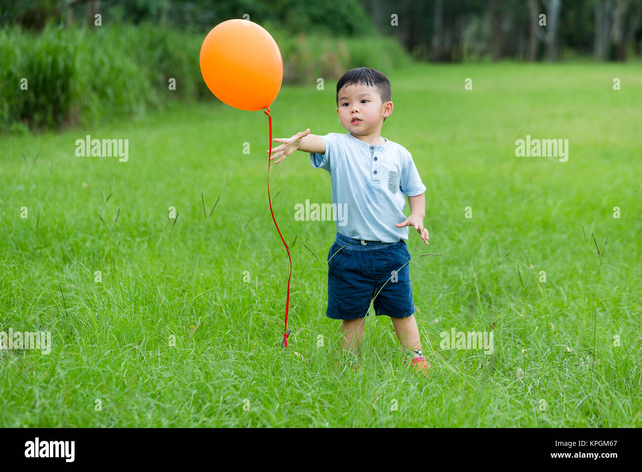 Asian kid want to catch with balloon at outdoor Stock Photo - Alamy