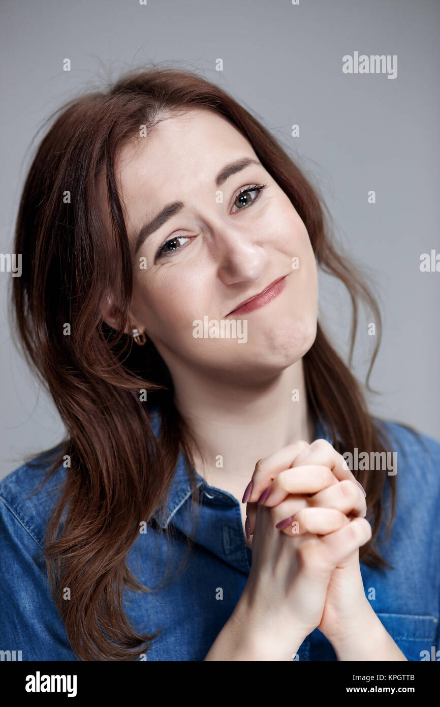 Woman is looking imploring over gray background Stock Photo - Alamy