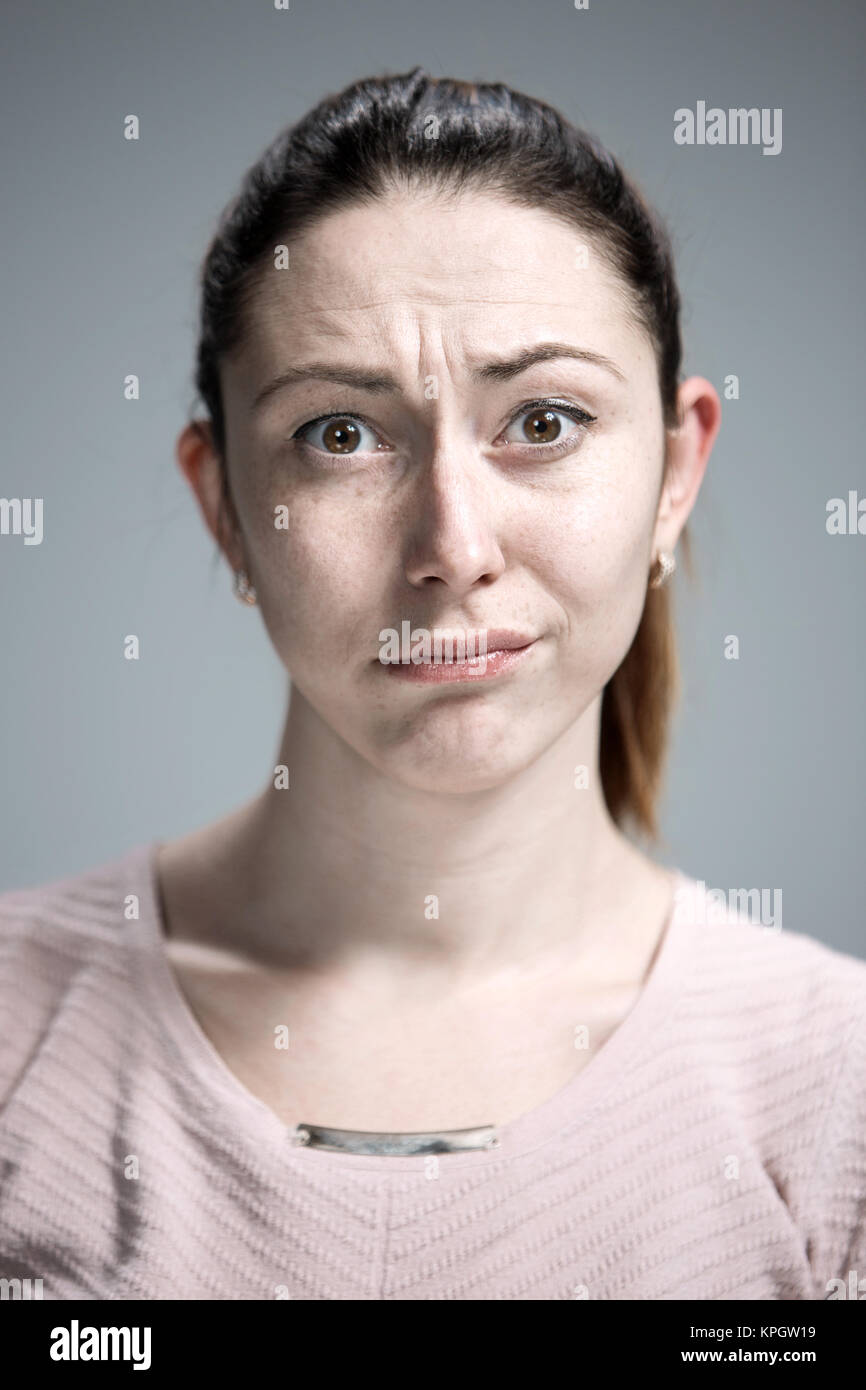 Woman is looking imploring over gray background Stock Photo - Alamy