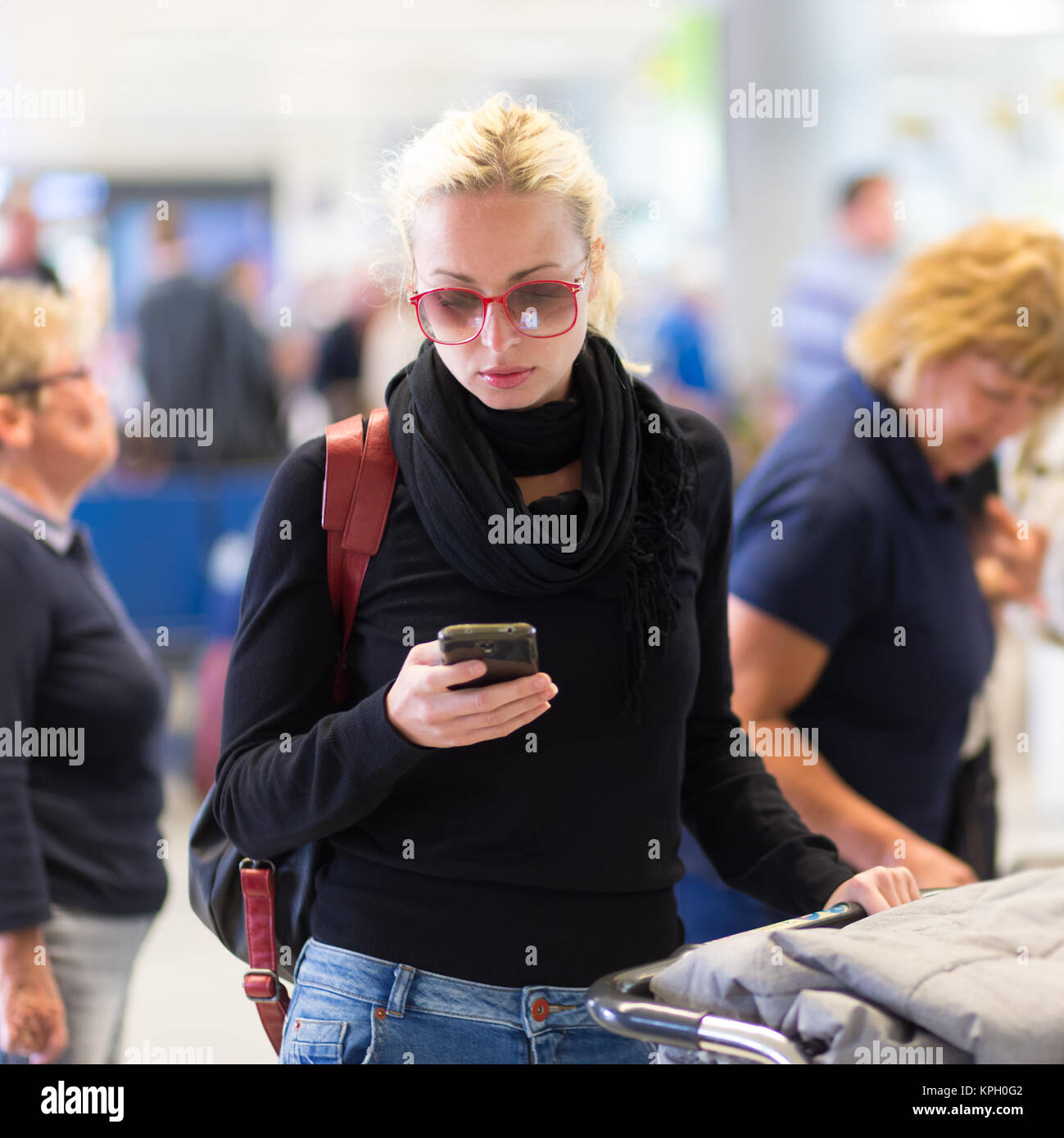 Female traveler using cell phone while waiting Stock Photo - Alamy