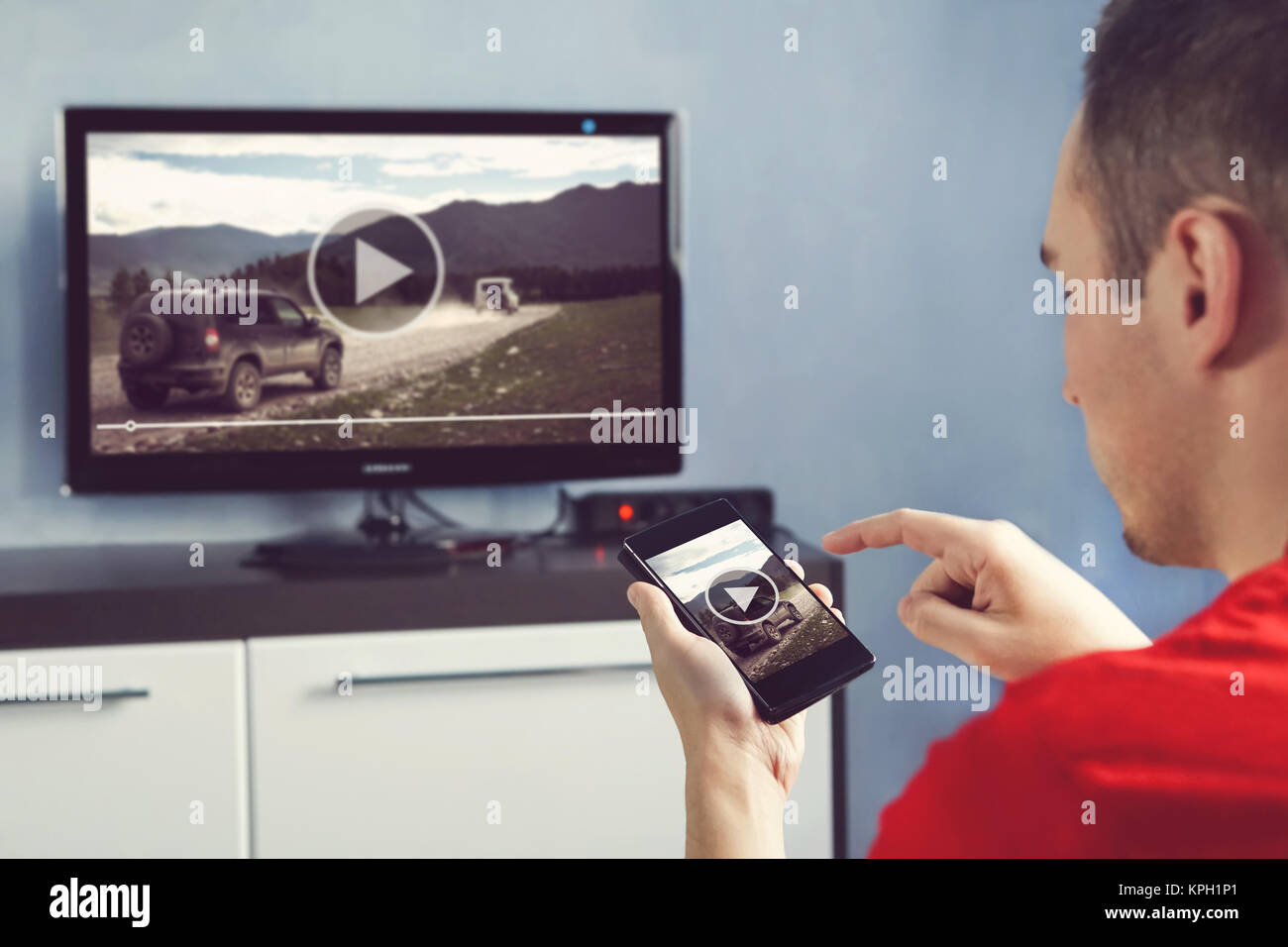 Man With Smartphone Connected To A TV Watching Video At Home. transfer ...