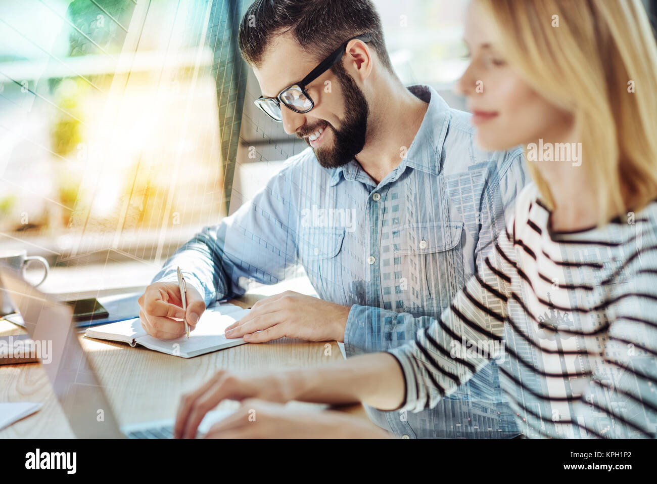 Two adult pleasant partners working by the table and sitting Stock ...