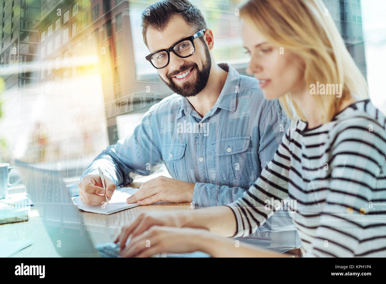 Handsome bespectacled man looking straight and writing Stock Photo - Alamy