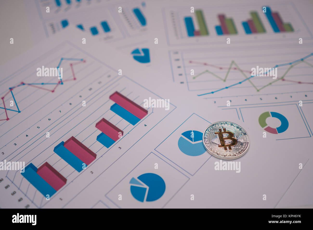 Silver coin with a gold symbol of Bitcoins is located on the charts ...