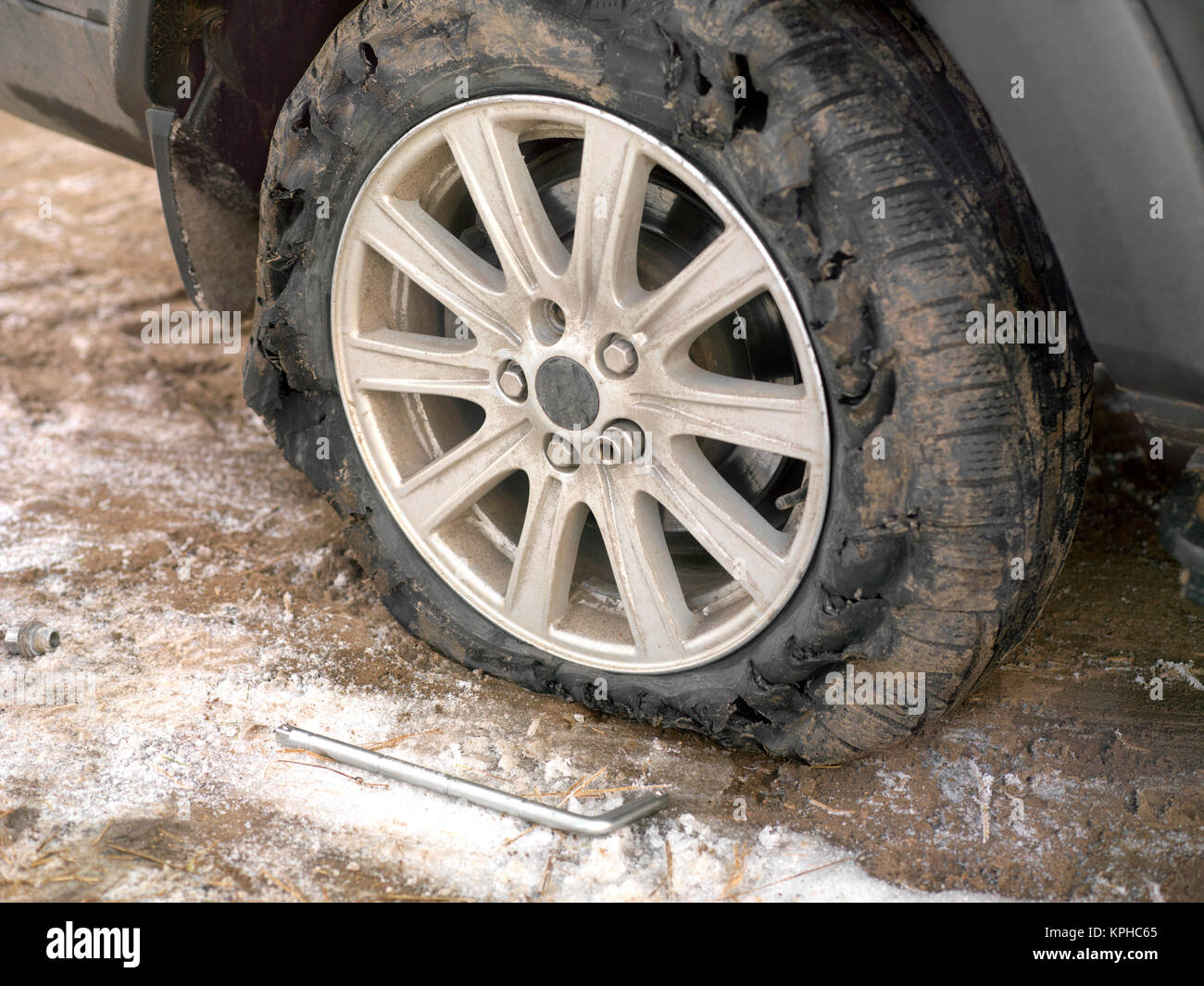 Deflated , completely destroyed tyre and wrench laid on the ground ...