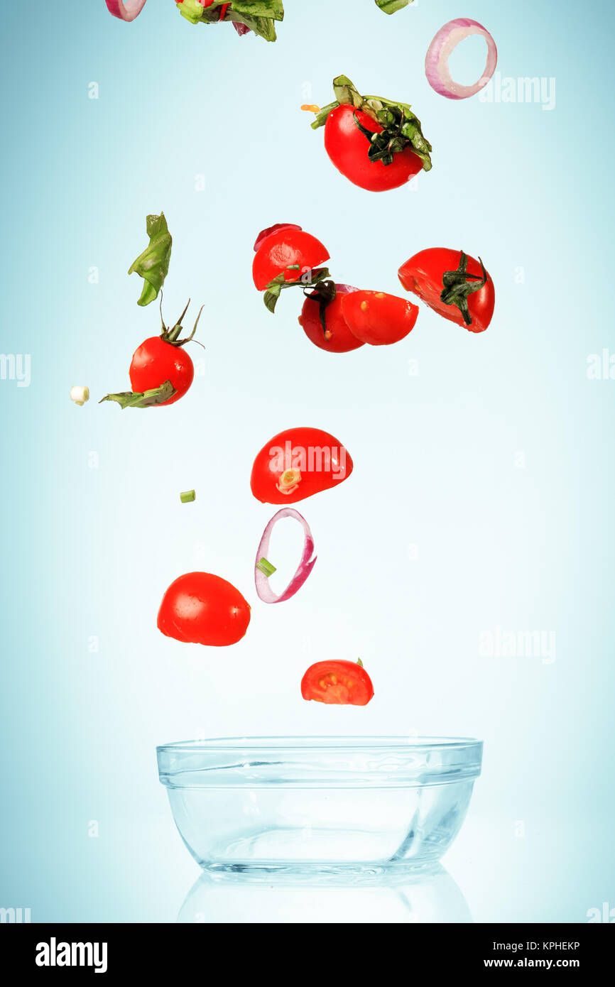 The vegetables for salad falling on blue Stock Photo - Alamy