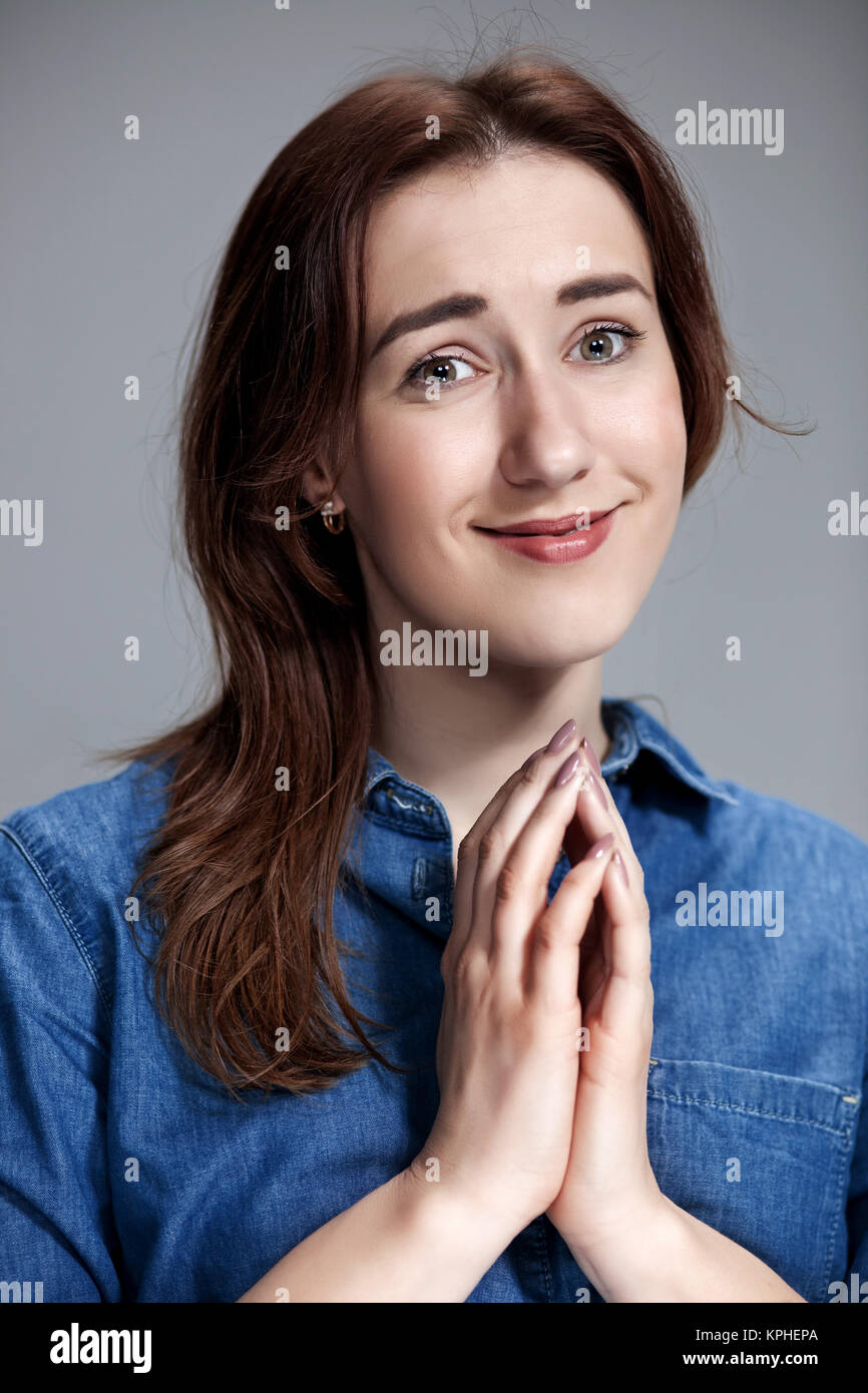 Woman is looking imploring over gray background Stock Photo - Alamy