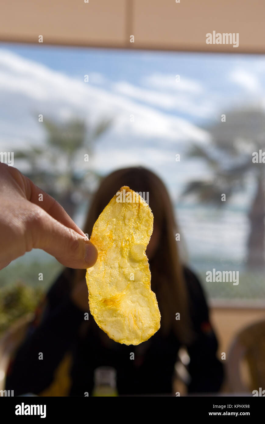 a hand holds up a single crisp hiding a person in the background Stock ...