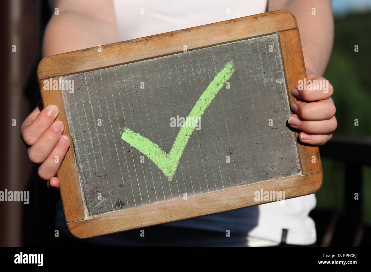green checkmark sketched with chalk on slate shown by young female ...