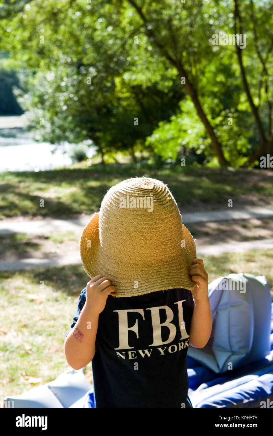 photo of small boy pulling an adult straw hat down over his face Stock ...