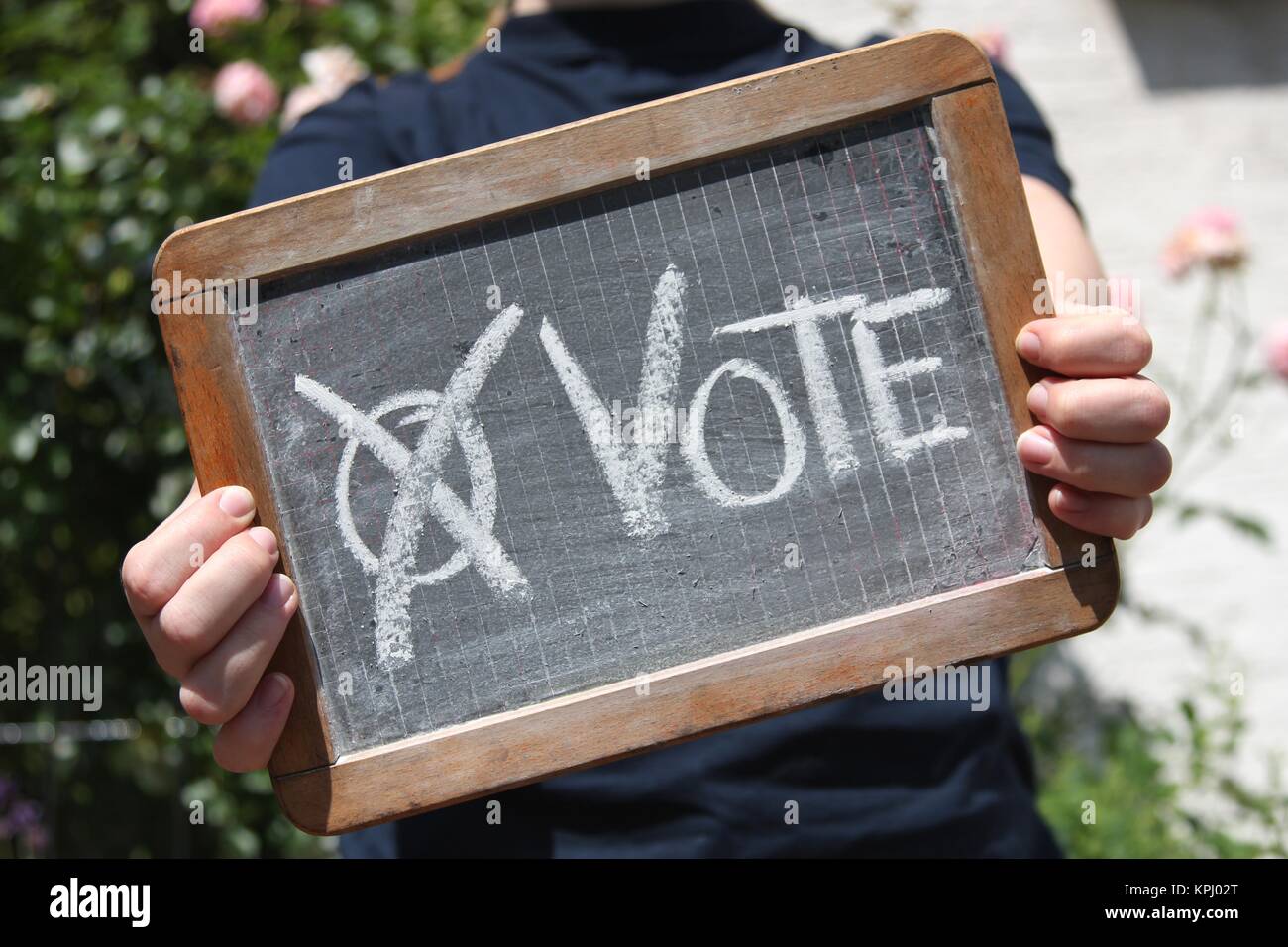 VOTE written with chalk on slate shown by young female Stock Photo - Alamy