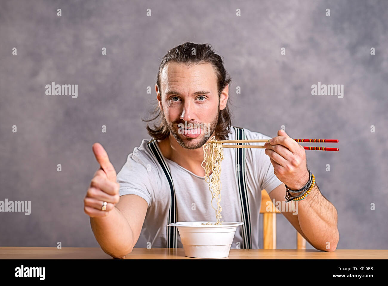 young man with thumb up and poked tongue eating asian food Stock Photo ...