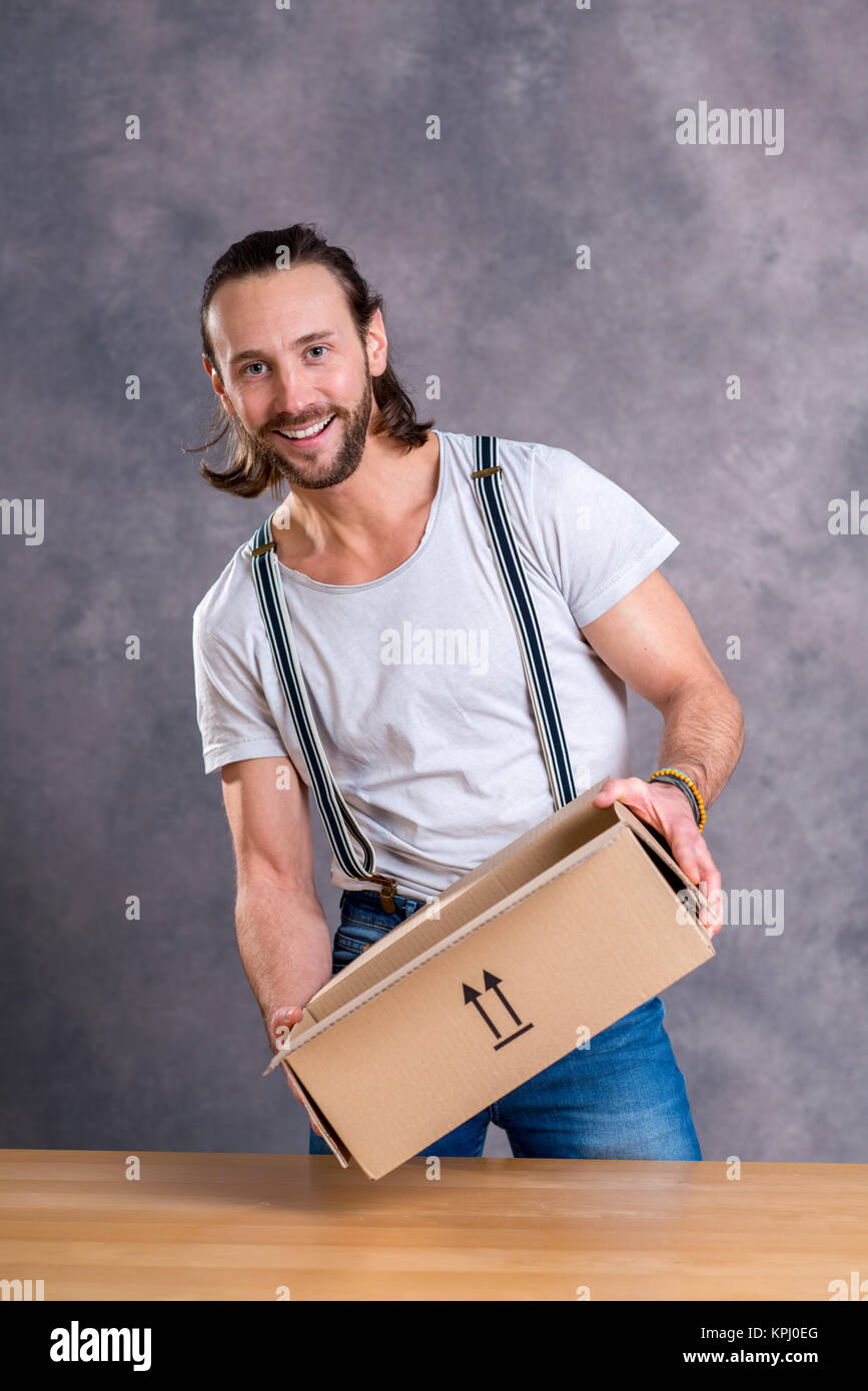 young man opening a package in front of gray background Stock Photo - Alamy