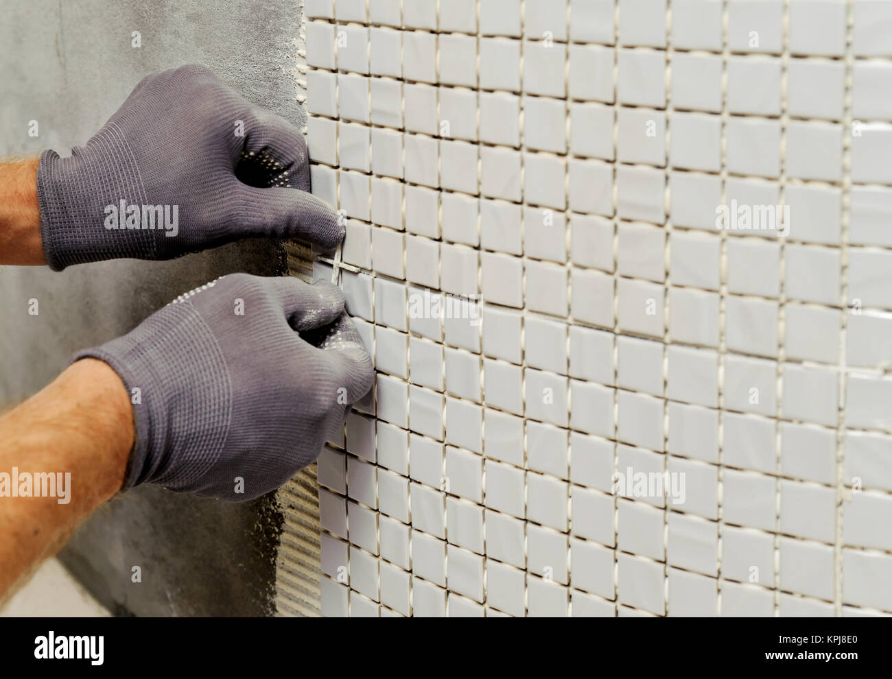 Installation of mosaic tiles. The worker fixes the tile to the base ...