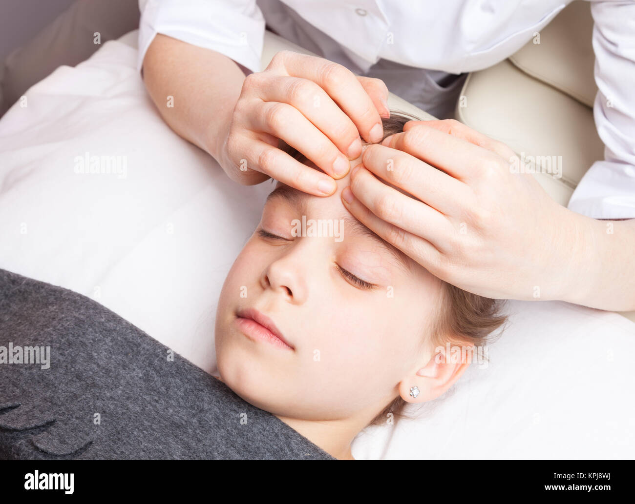 Elementary age girl's forehead being manipulated by osteopathic manual ...