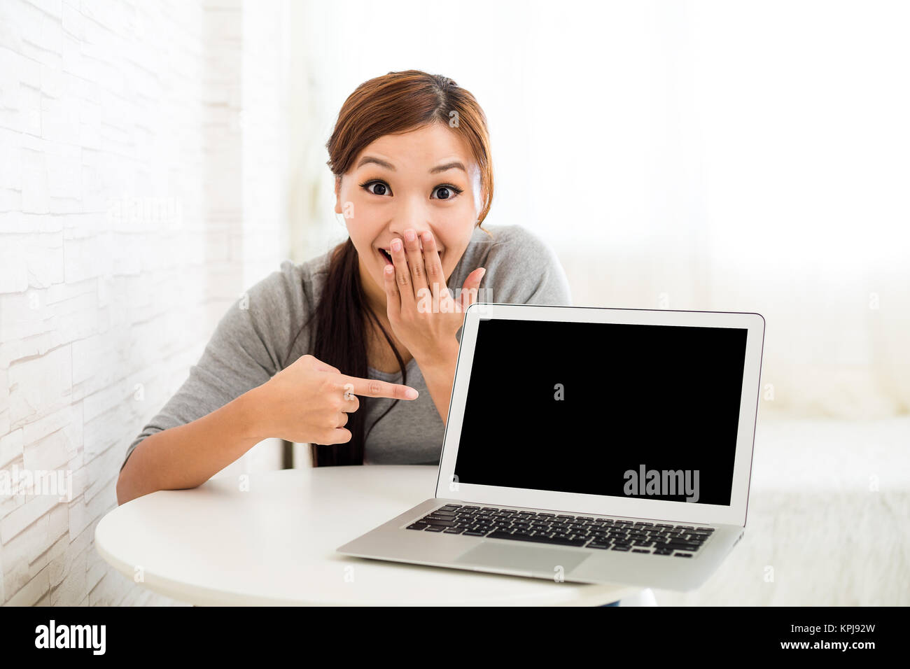 Excited young woman showing laptop computer Stock Photo - Alamy