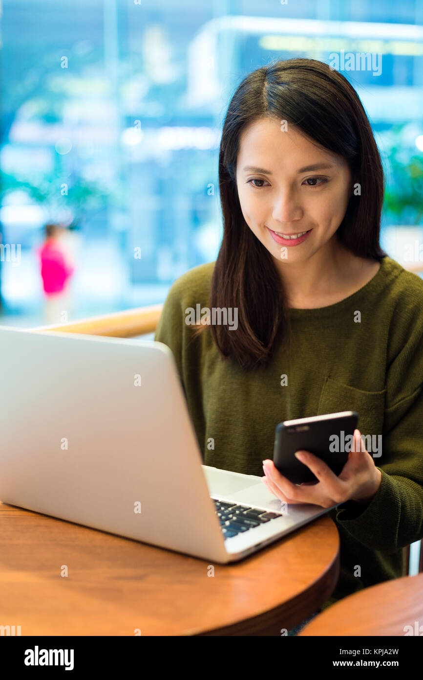 Woman use of cellphone and laptop computer at coffee shop Stock Photo ...