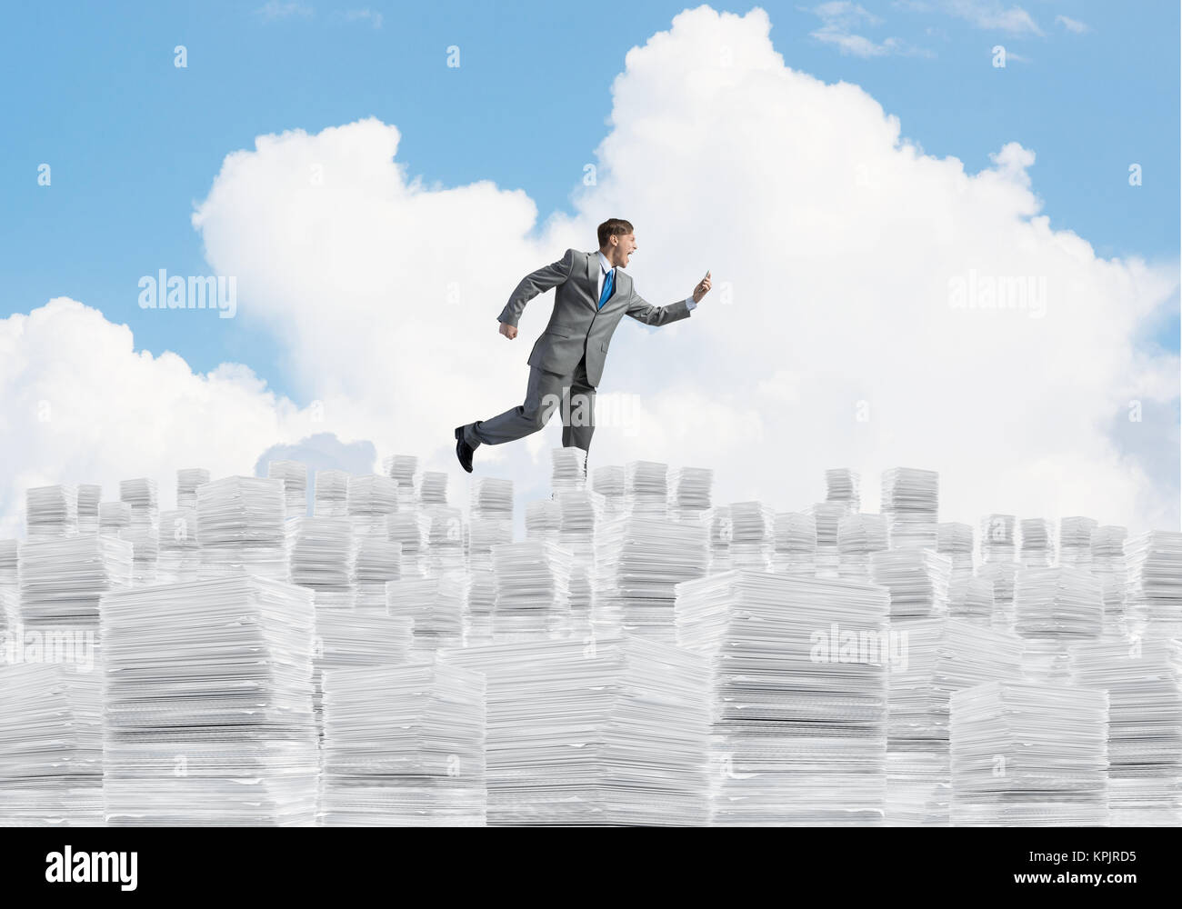 Businessman in black suit running with phone in hand on pile of ...