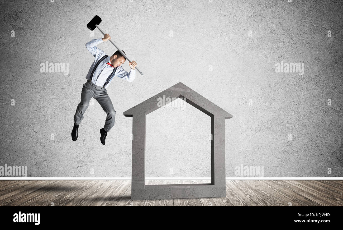 Determined businessman going to break with hammer house concrete figure ...