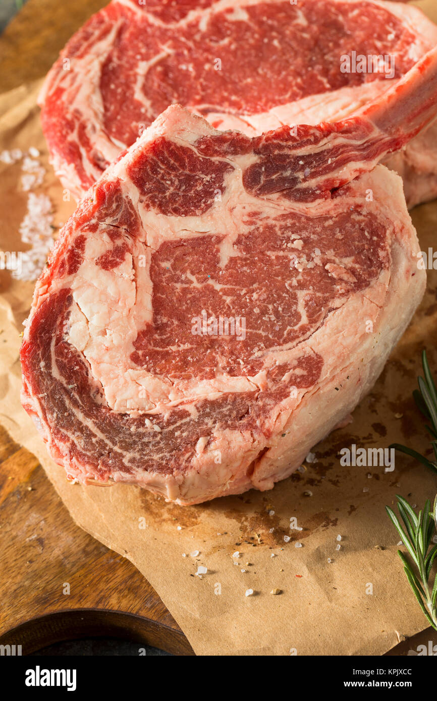 Raw Red Grass Fed Tomahawk Steaks with Rosemary Stock Photo - Alamy