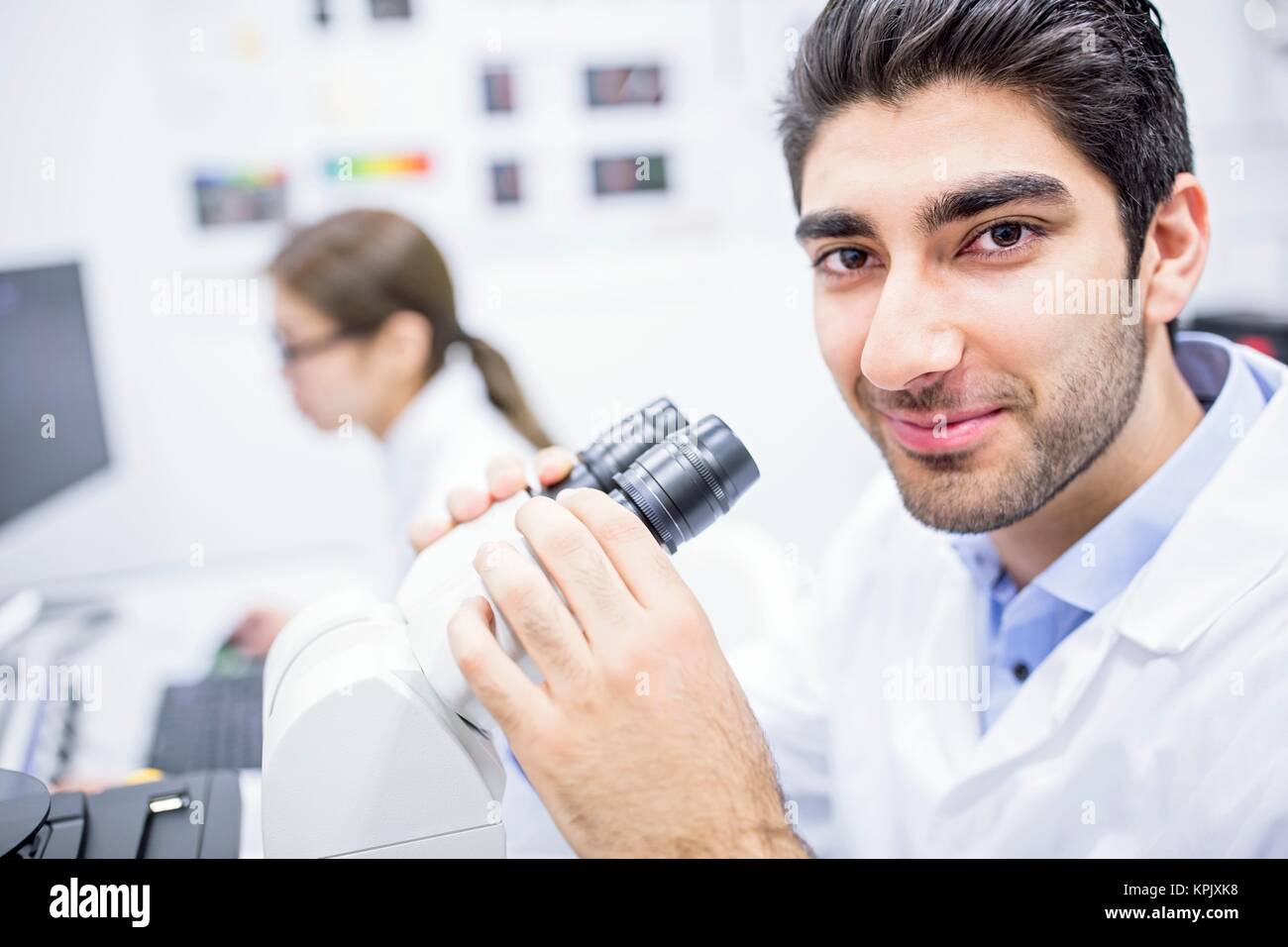 Male scientist using microscope, looking at camera Stock Photo - Alamy