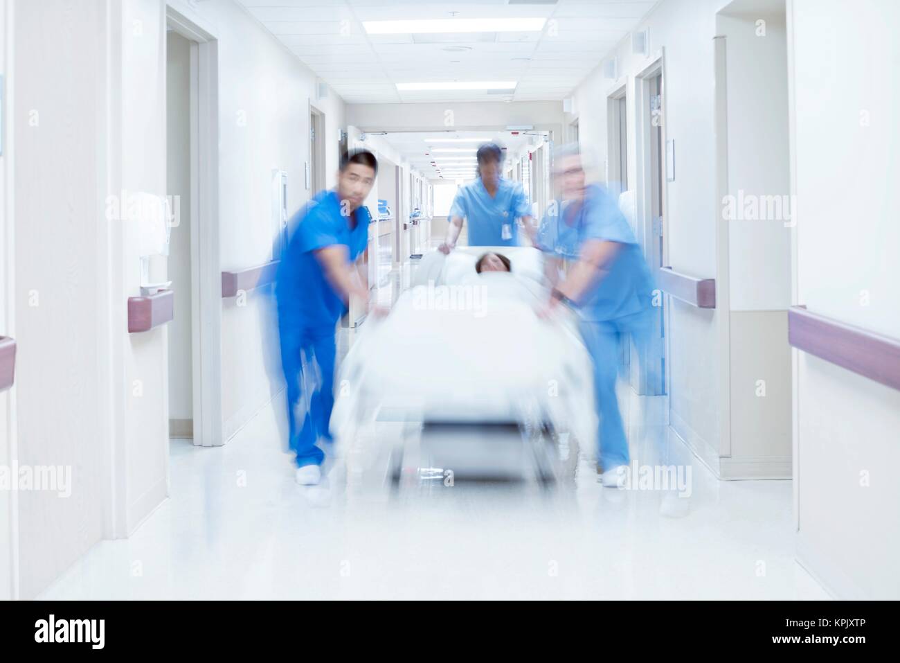 Medical team pushing patient on bed through corridor Stock Photo - Alamy