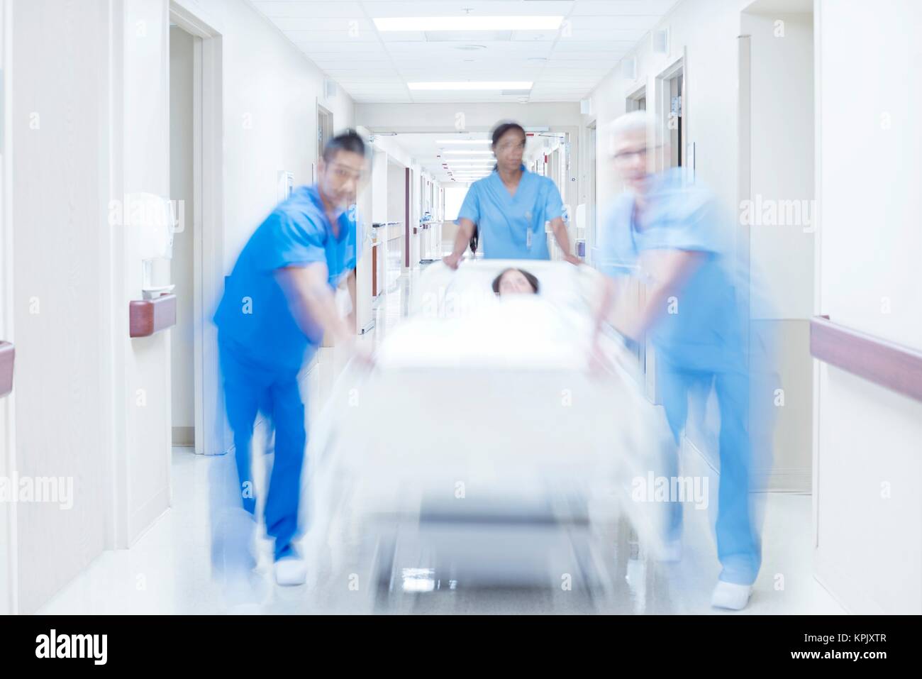 Medical team pushing patient on bed through corridor Stock Photo - Alamy