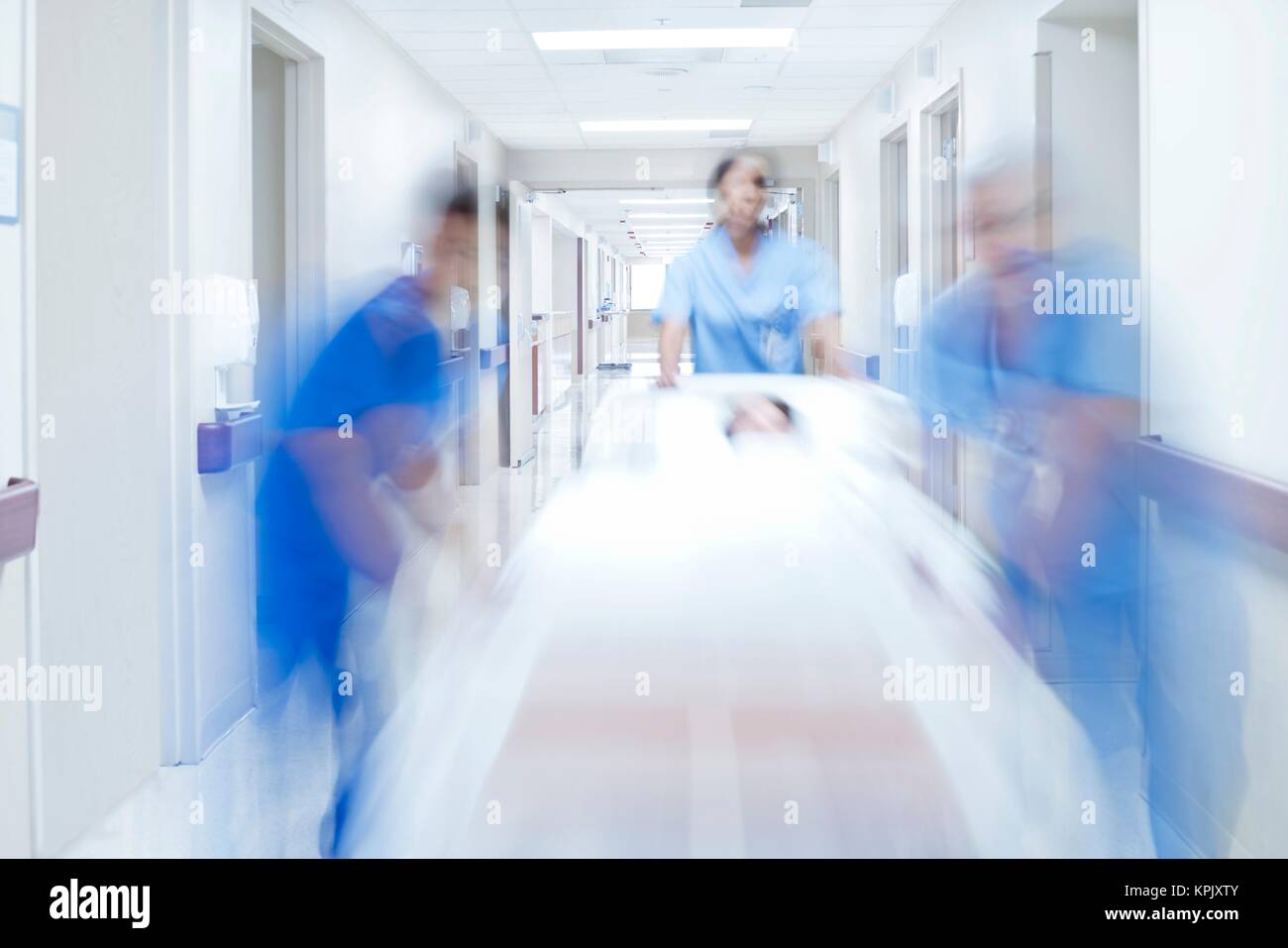 Medical team pushing patient on bed through corridor Stock Photo - Alamy