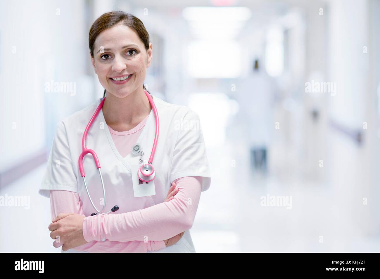 Nurse smiling towards camera with arms folded, portrait Stock Photo - Alamy