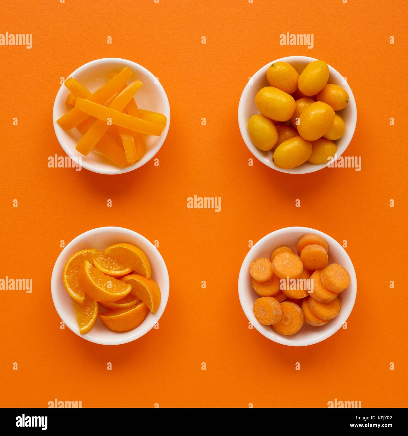 Orange produce in dishes against a red background Stock Photo - Alamy