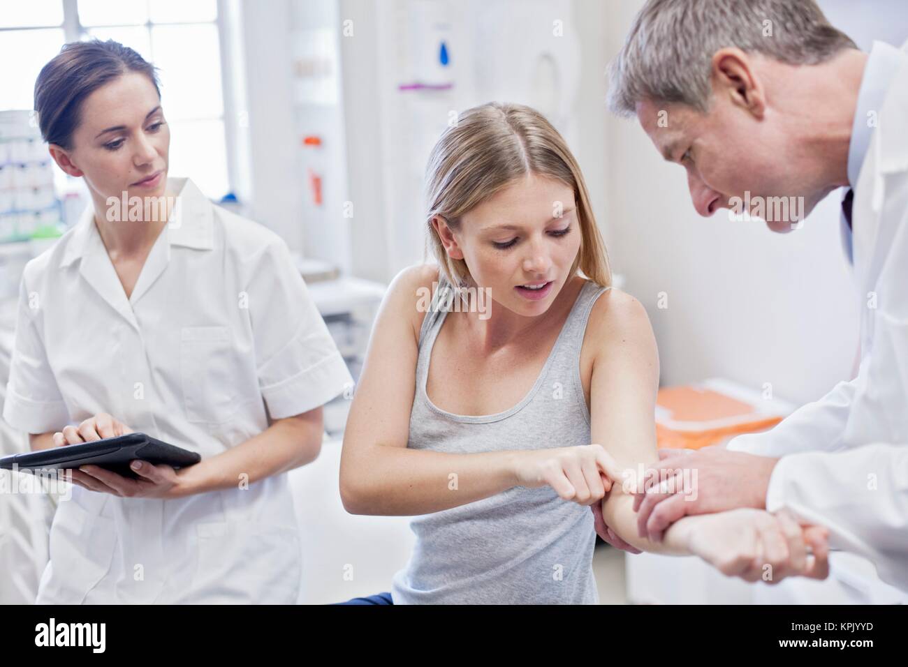 Male doctor examining young woman's arm Stock Photo - Alamy