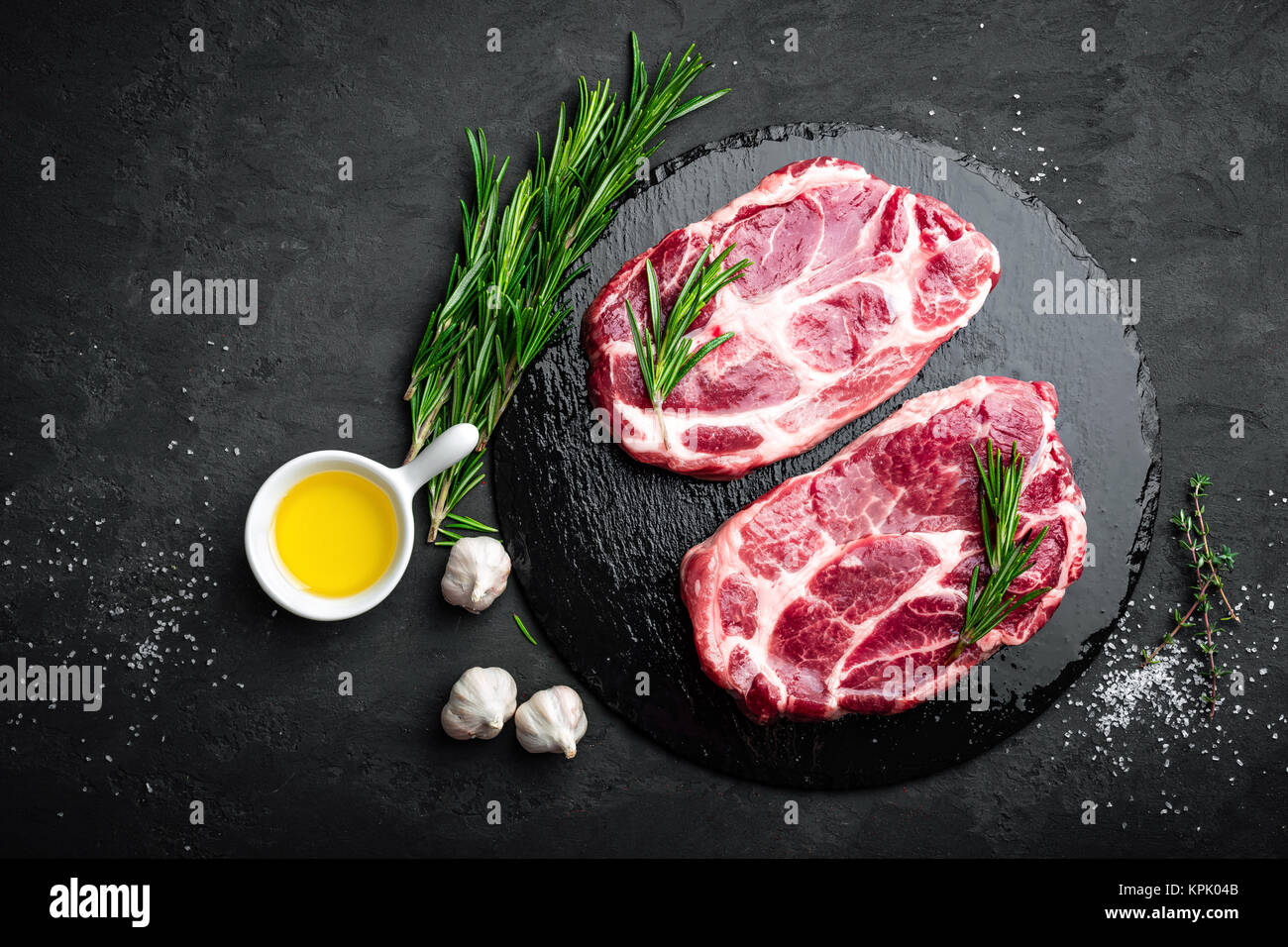 Cooking on kitchen table fresh raw pork marbled steaks on black ...