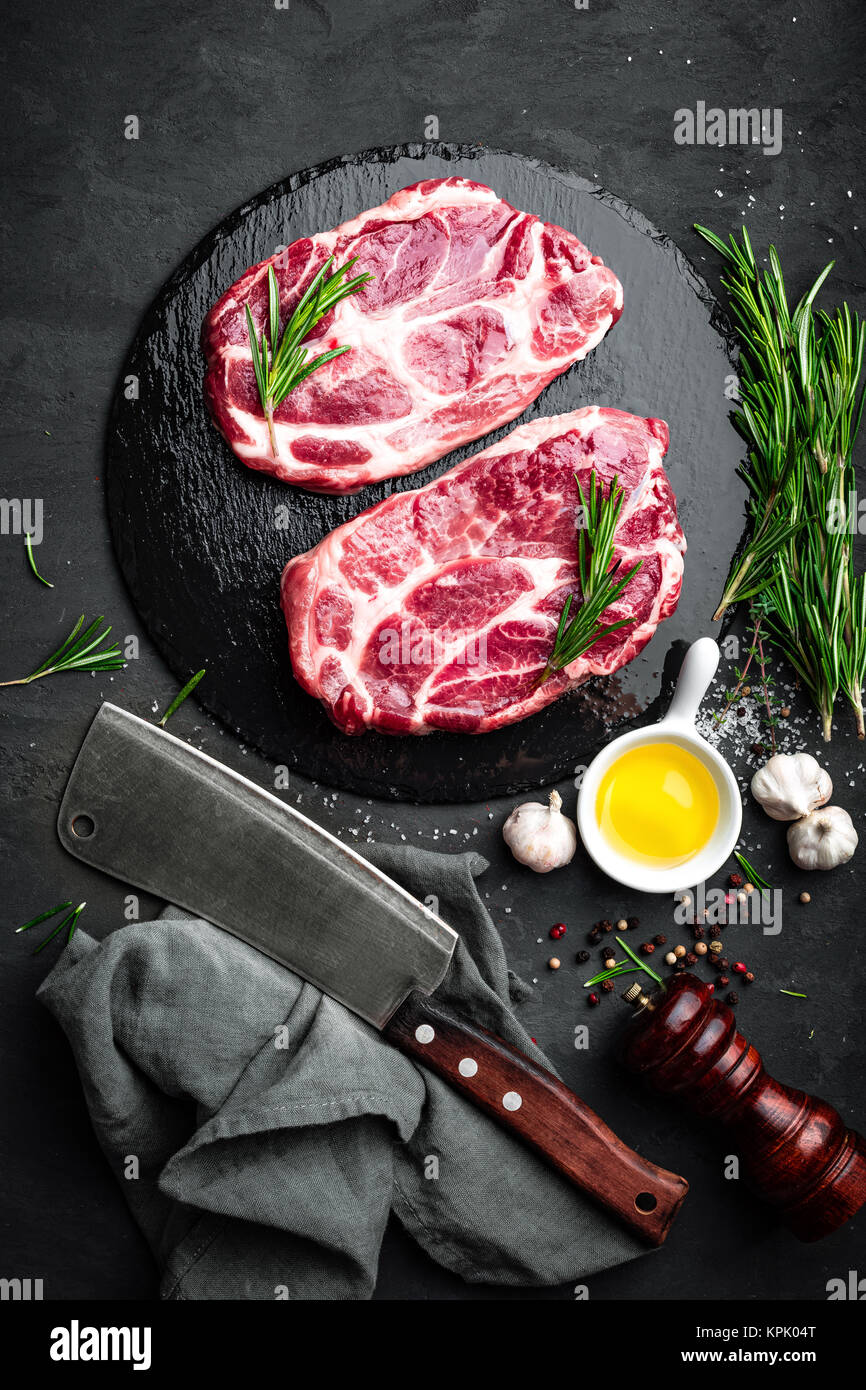Cooking on kitchen table fresh raw pork marbled steaks on black ...