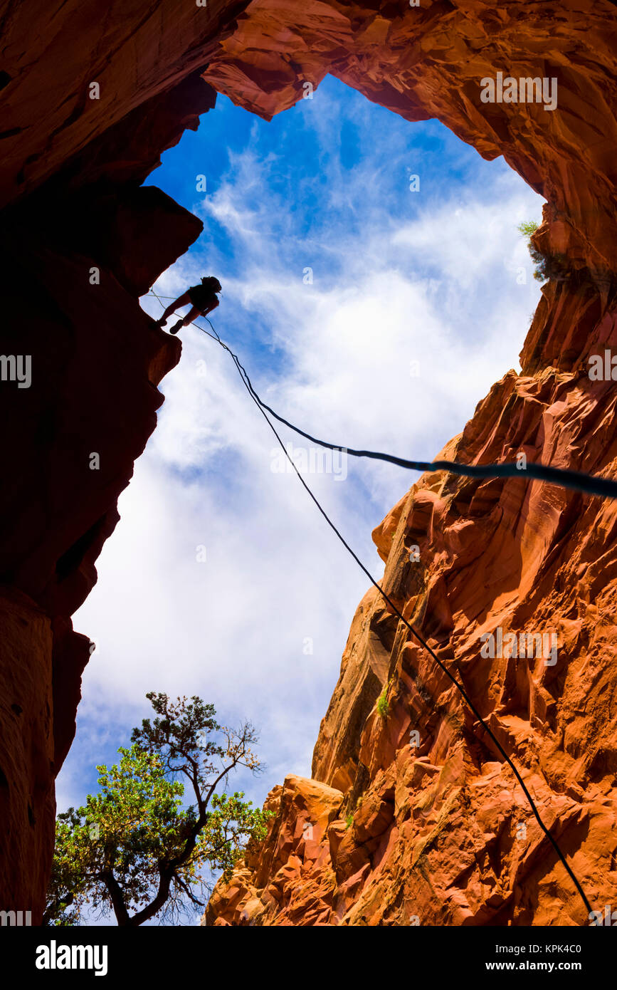 Looking upwards to the silhouette of an adventurer rappelling down a ...
