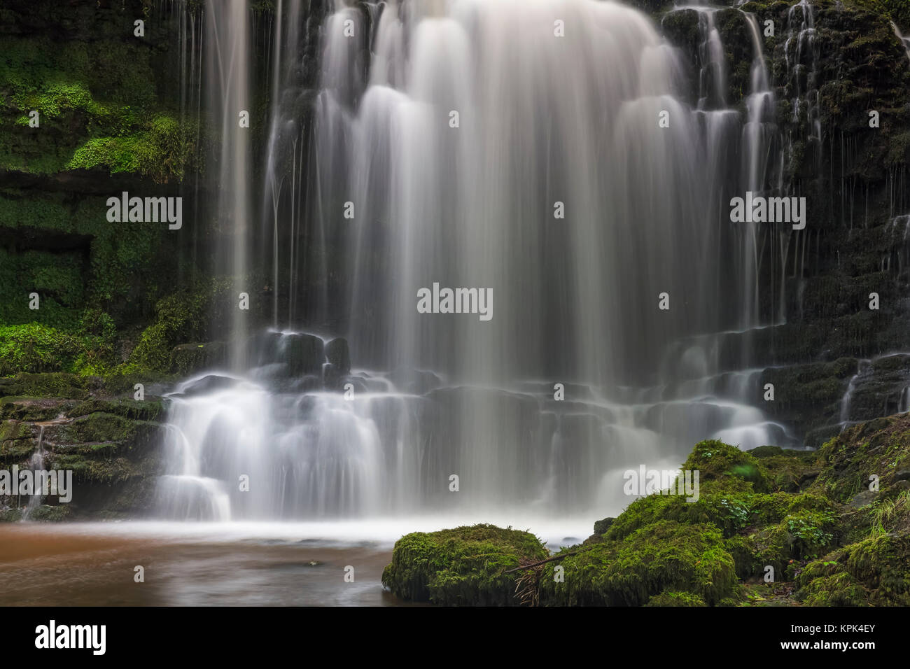 Numerous waterfalls flowing over rocks into a pool in the Yorkshire ...