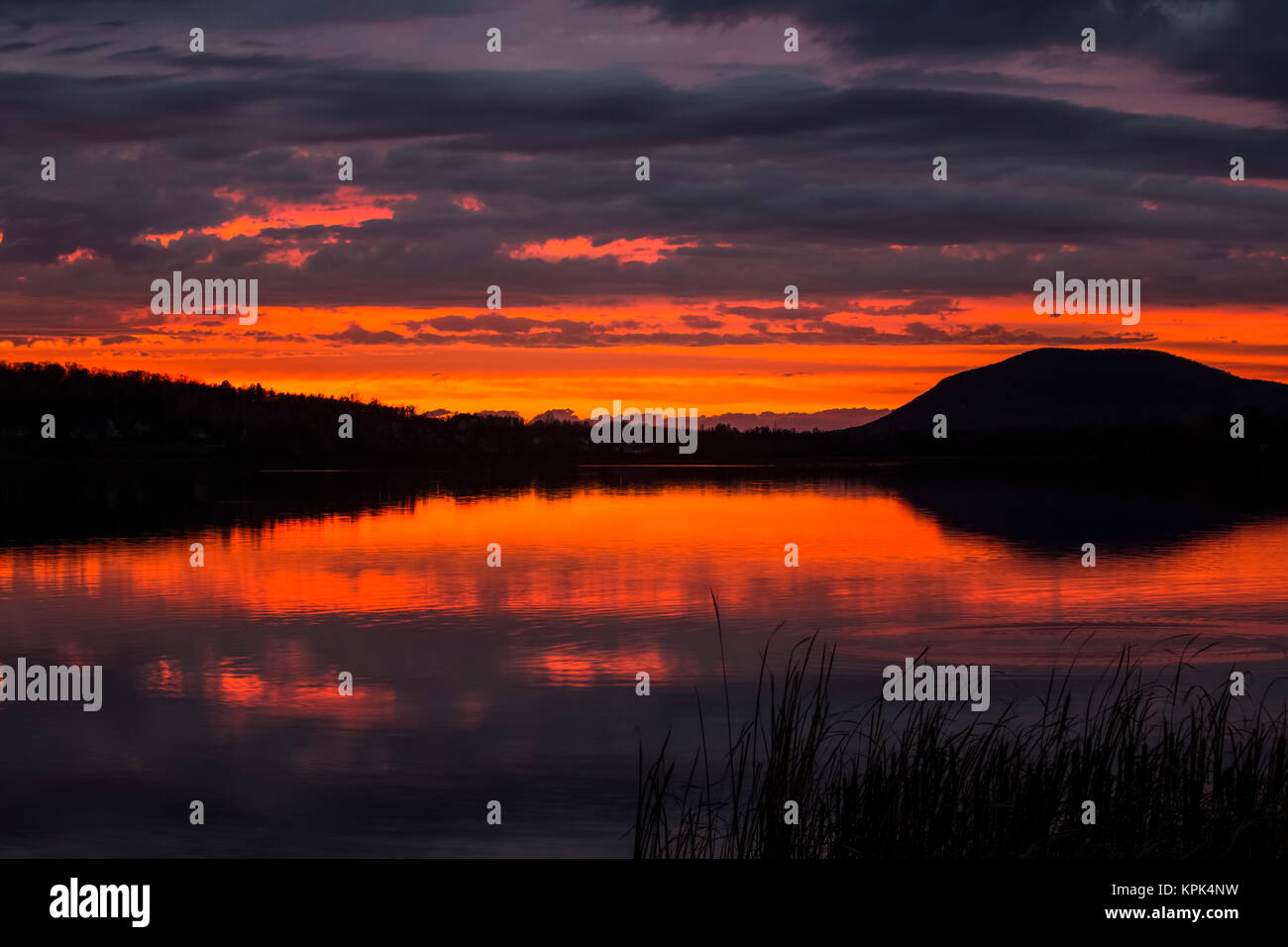 Sunset with vibrant colours reflecting on the tranquil water of ...