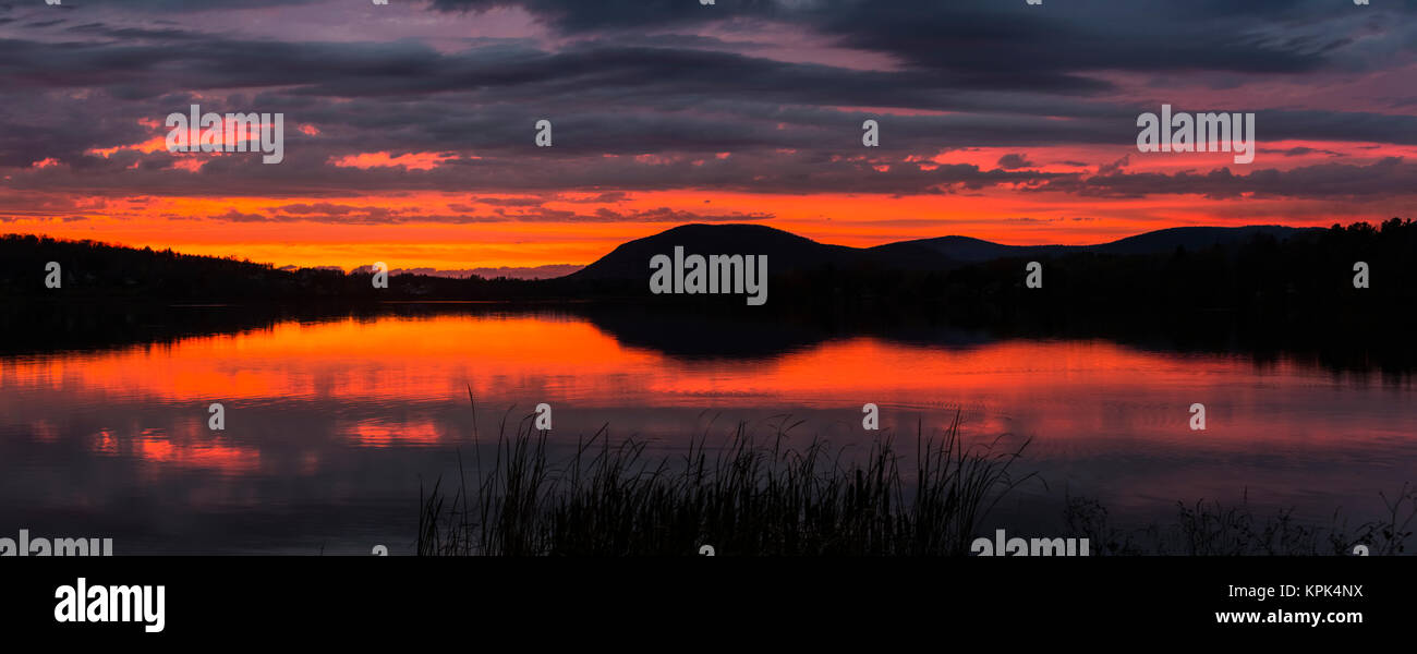 Sunset with vibrant colours reflecting on the tranquil water of ...
