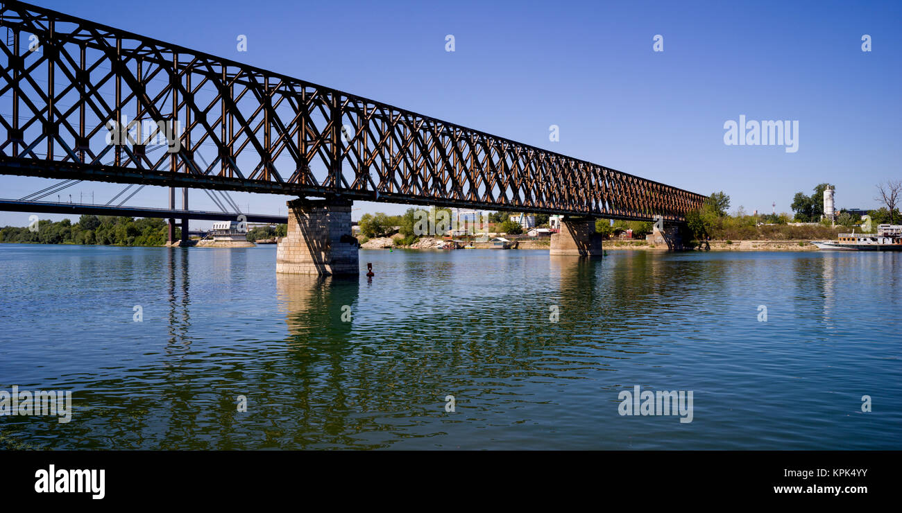 A bridge crossing the Sava River reflected in the water with blue sky ...