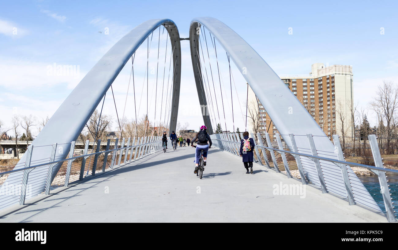 Pedestrians and cyclists going across a bridge over the Bow River ...