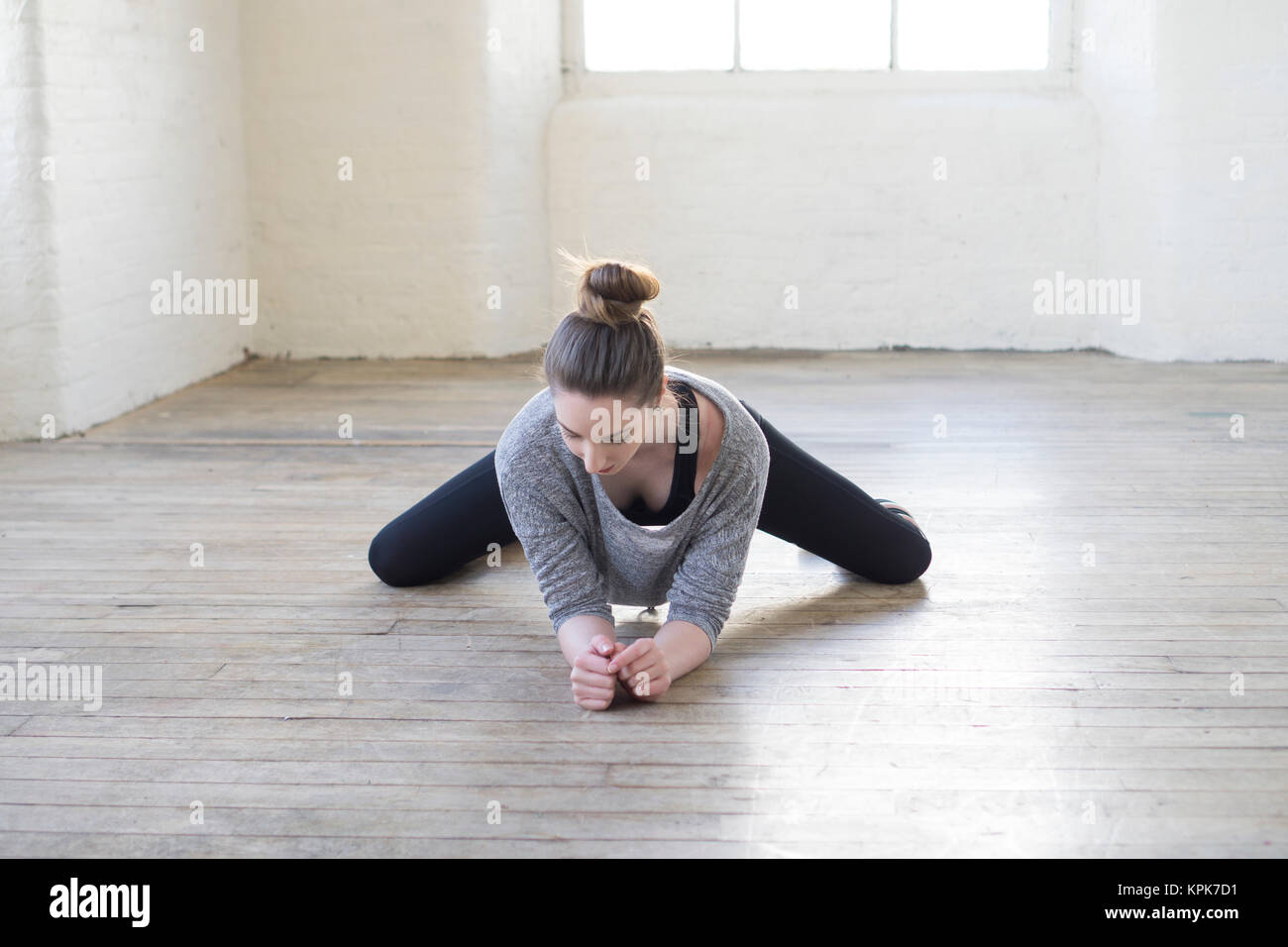 Healthy young woman stretching legs on the floor Stock Photo - Alamy