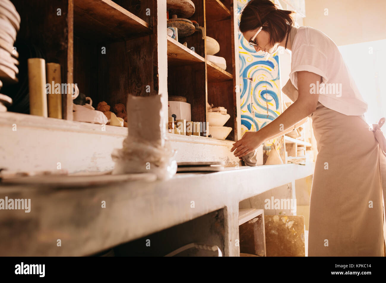 Woman kneading clay for pot making. Craftswoman preparing clay for pot ...