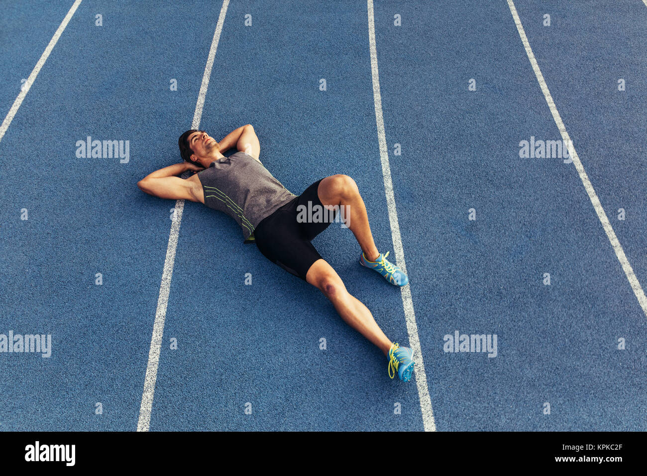Runner lying on the track in a relaxed mood with hands under his head ...